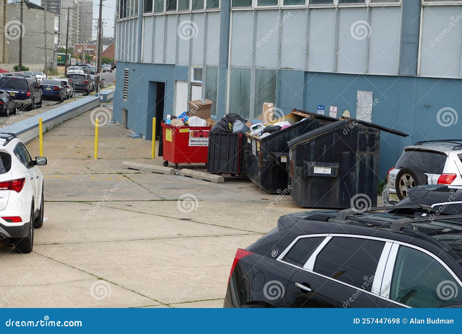 Multiple Small Dumpsters Full of Trash by the Side of a Building ...