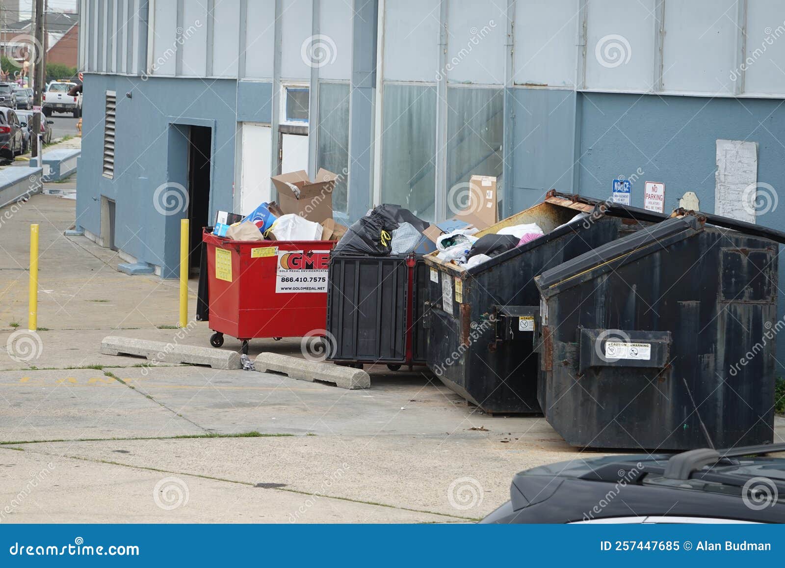 Multiple Small Dumpsters Full of Trash by the Side of a Building ...
