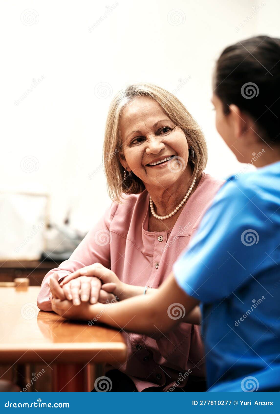 Attending To Her Client A Female Nurse And A Senior Woman In A
