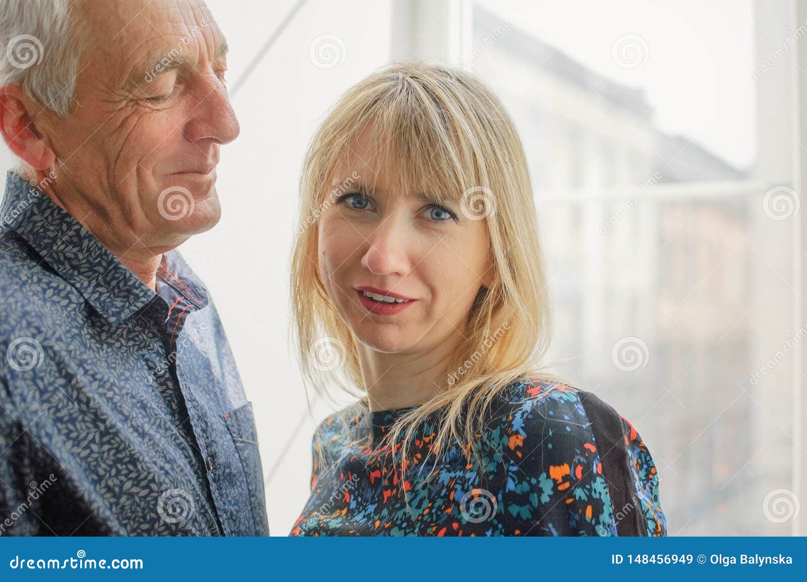 Attractive Blond Woman Hugging Handsome Senior Man And Looking At The