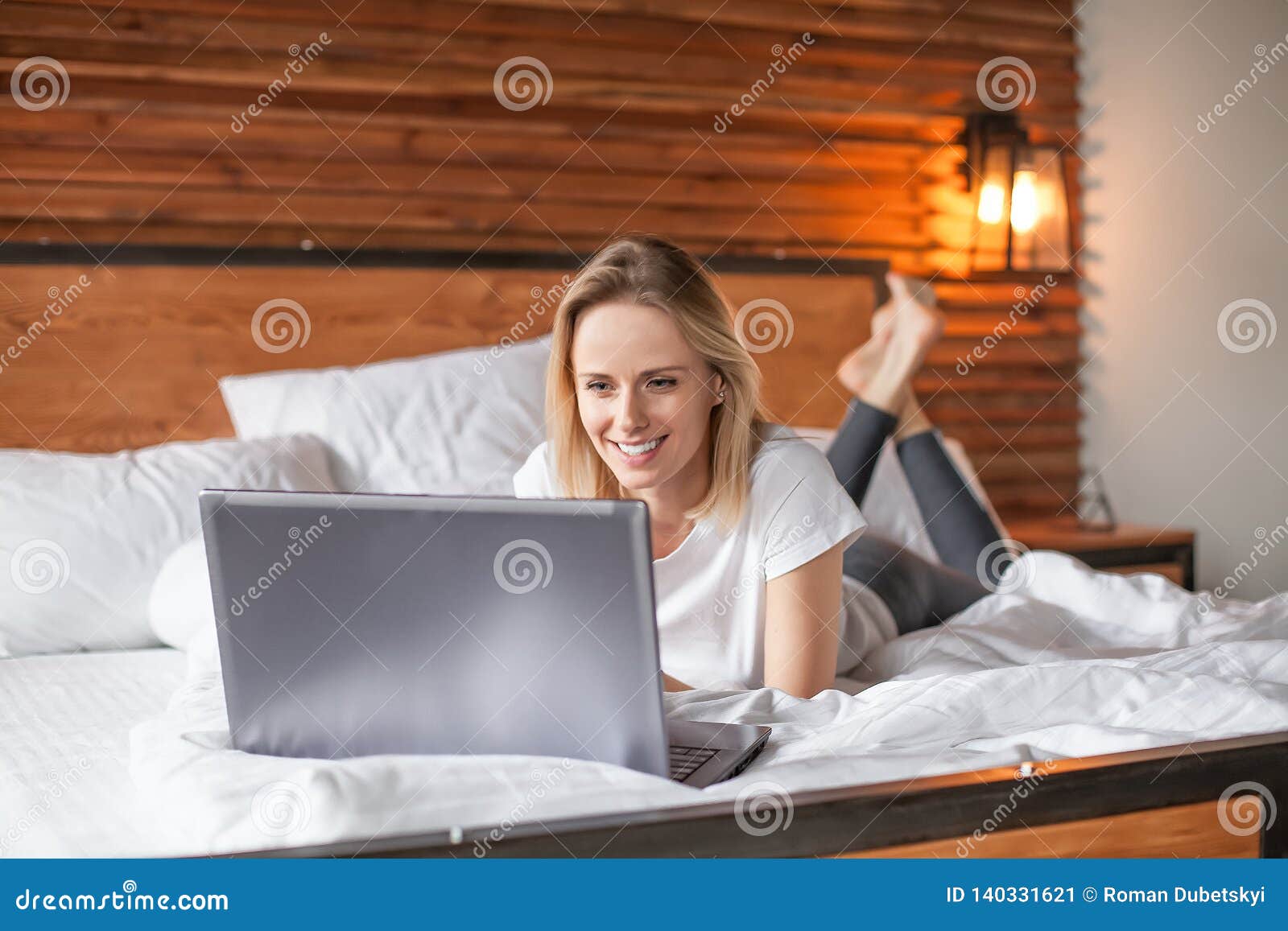 Attractive Blonde Woman Using Notebook Computer while Lying in Bed ...