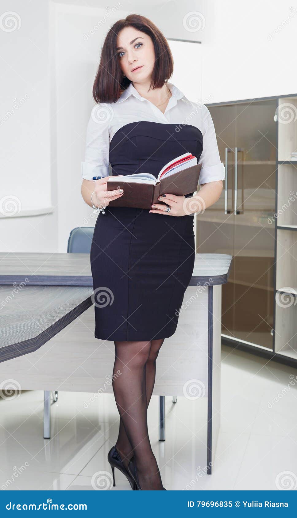 Attractive Dark Haired Woman Wearing A Black And White Dress Standing