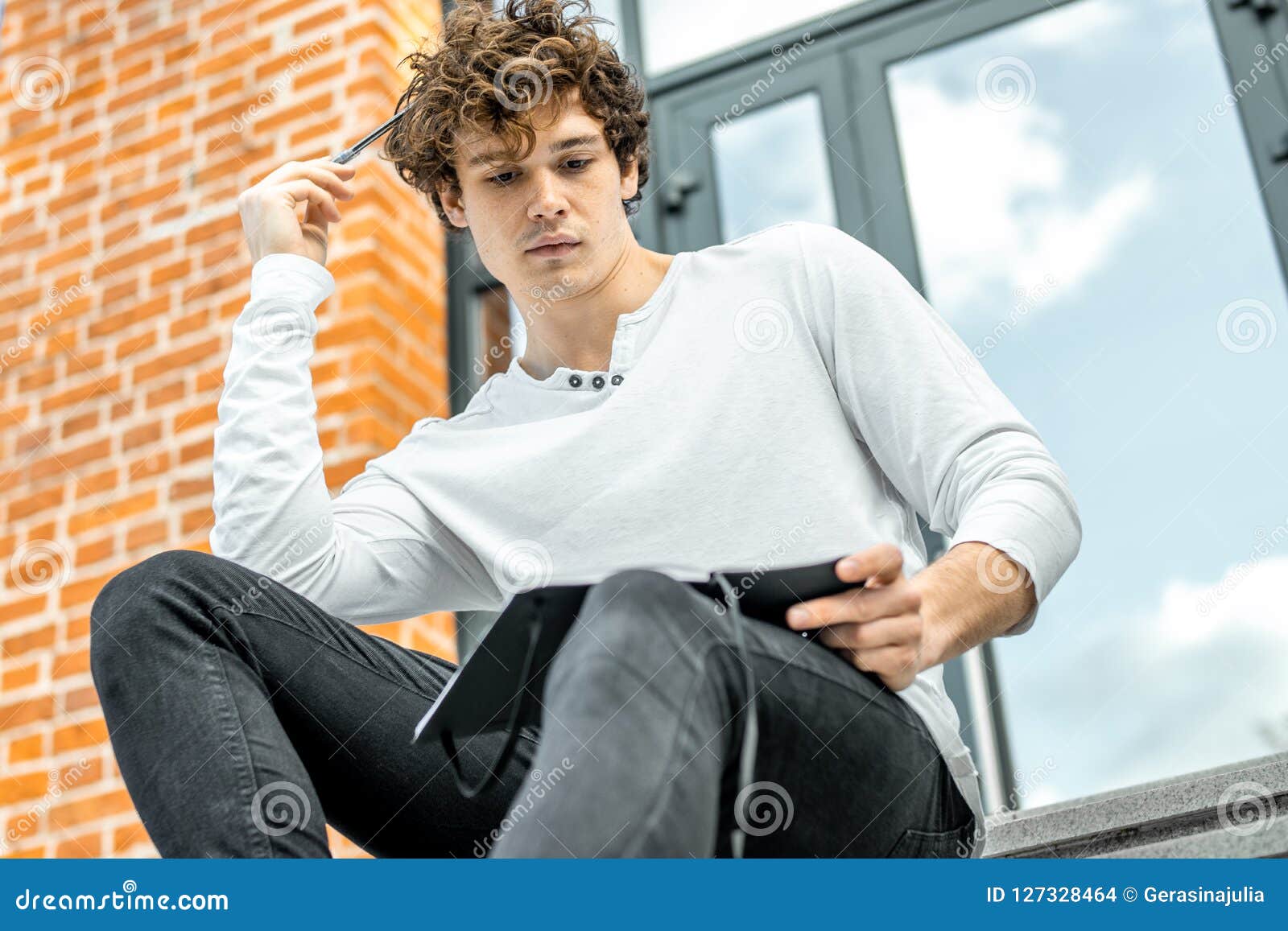 Attractive Man Holding Notepad in His Hands and Sitting on Concrete ...