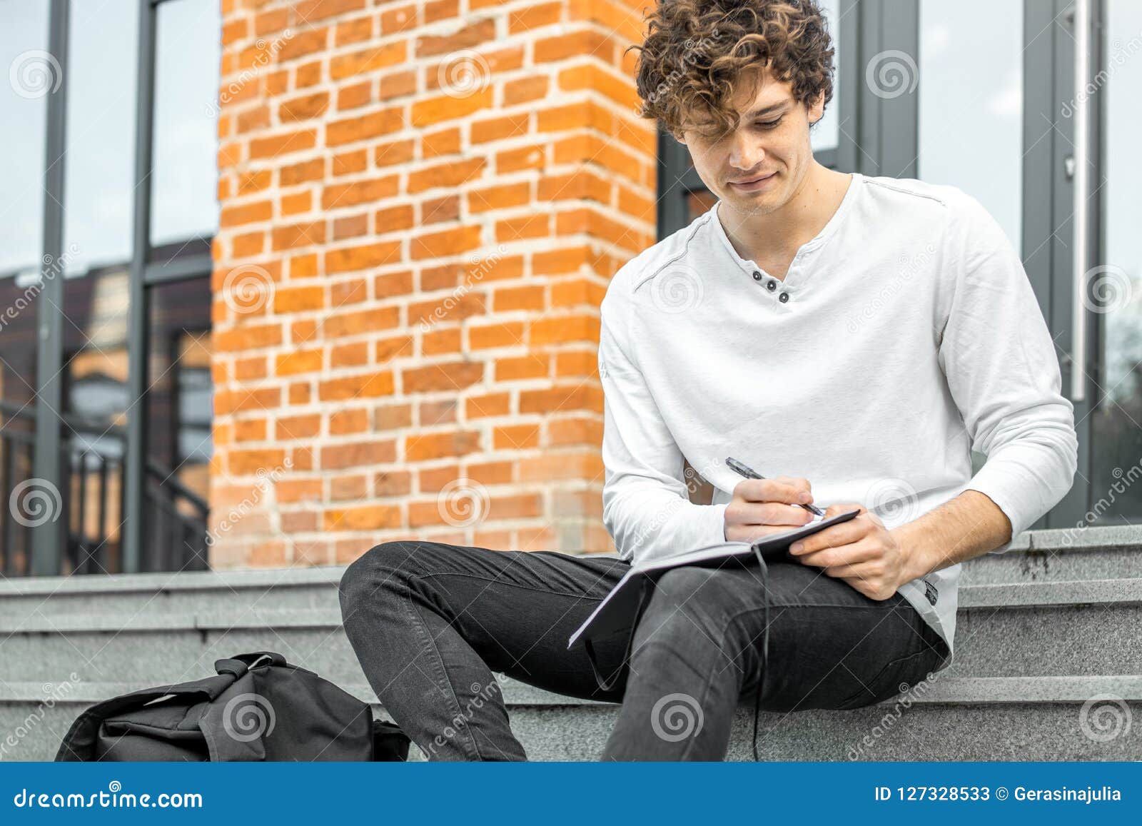 Attractive Man Holding Notepad in His Hands and Sitting on Concrete ...