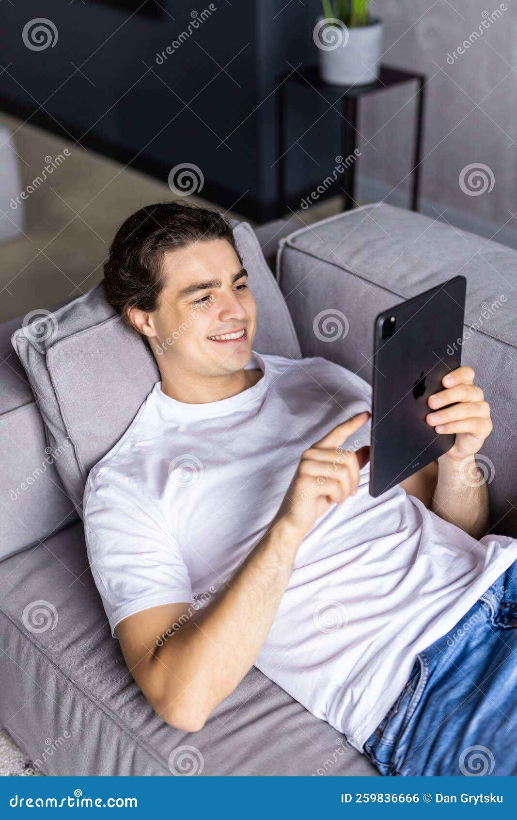 Attractive Man Using Digital Pad or Tablet Lying Relaxed on Couch at ...