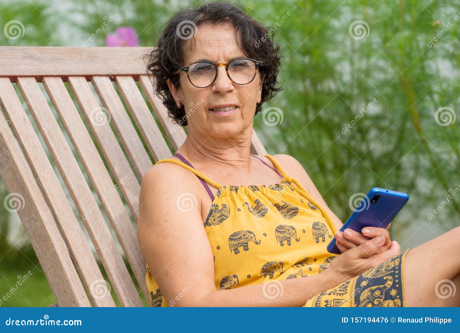 Mature Woman Relaxing in a Garden Holding and Using Smartphone Mobile ... Mature Woman Relaxing in a Garden Holding and Using Smartphone Mobile ...