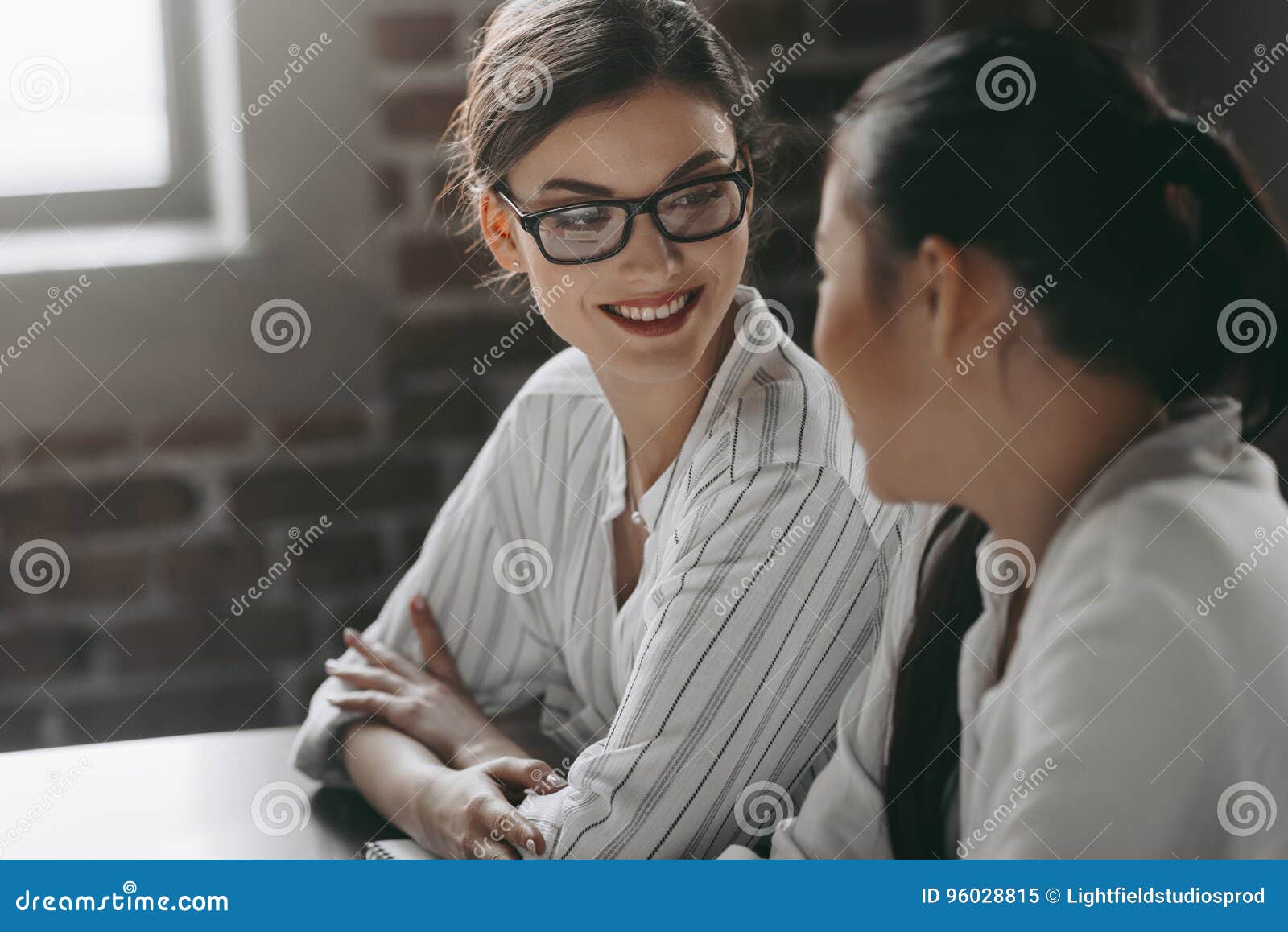 Attractive Multicultural Businesswomen Talking while Sitting in Modern ...