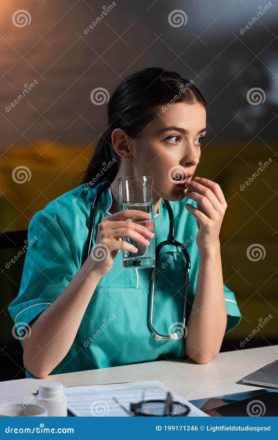 Nurse in Uniform Sitting at Table and Taking Pill during Night Shift ...