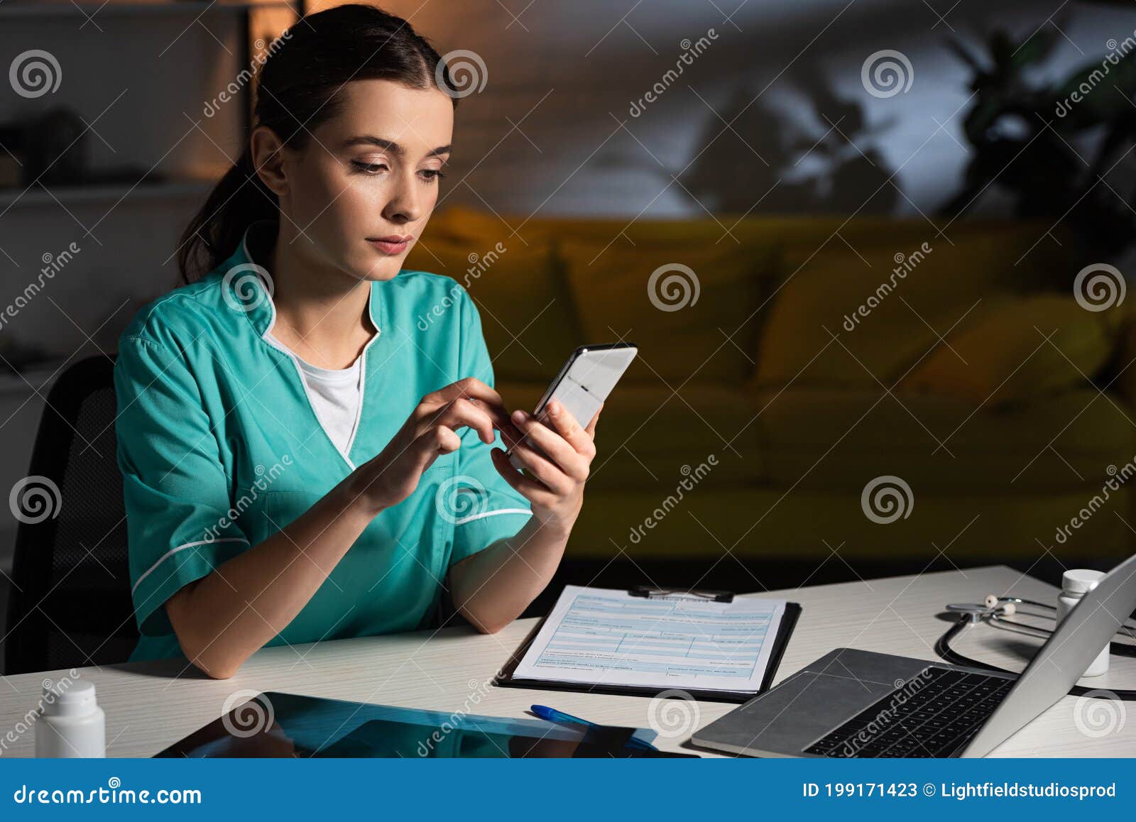 Nurse in Uniform Sitting at Table and Using Smartphone during Night ...