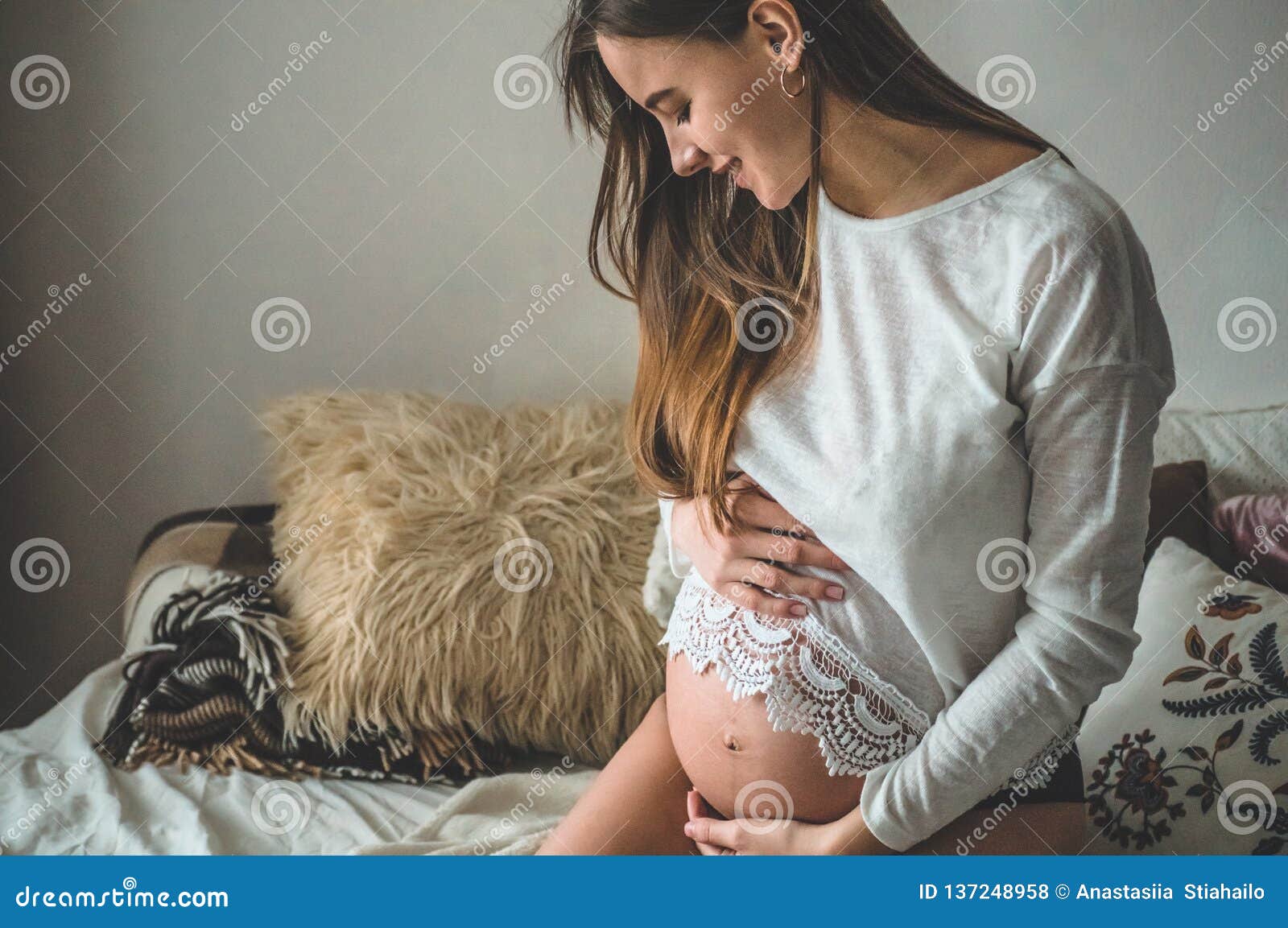 Attractive Pregnant Woman Is Sitting In Bed And Holding Her Belly Last