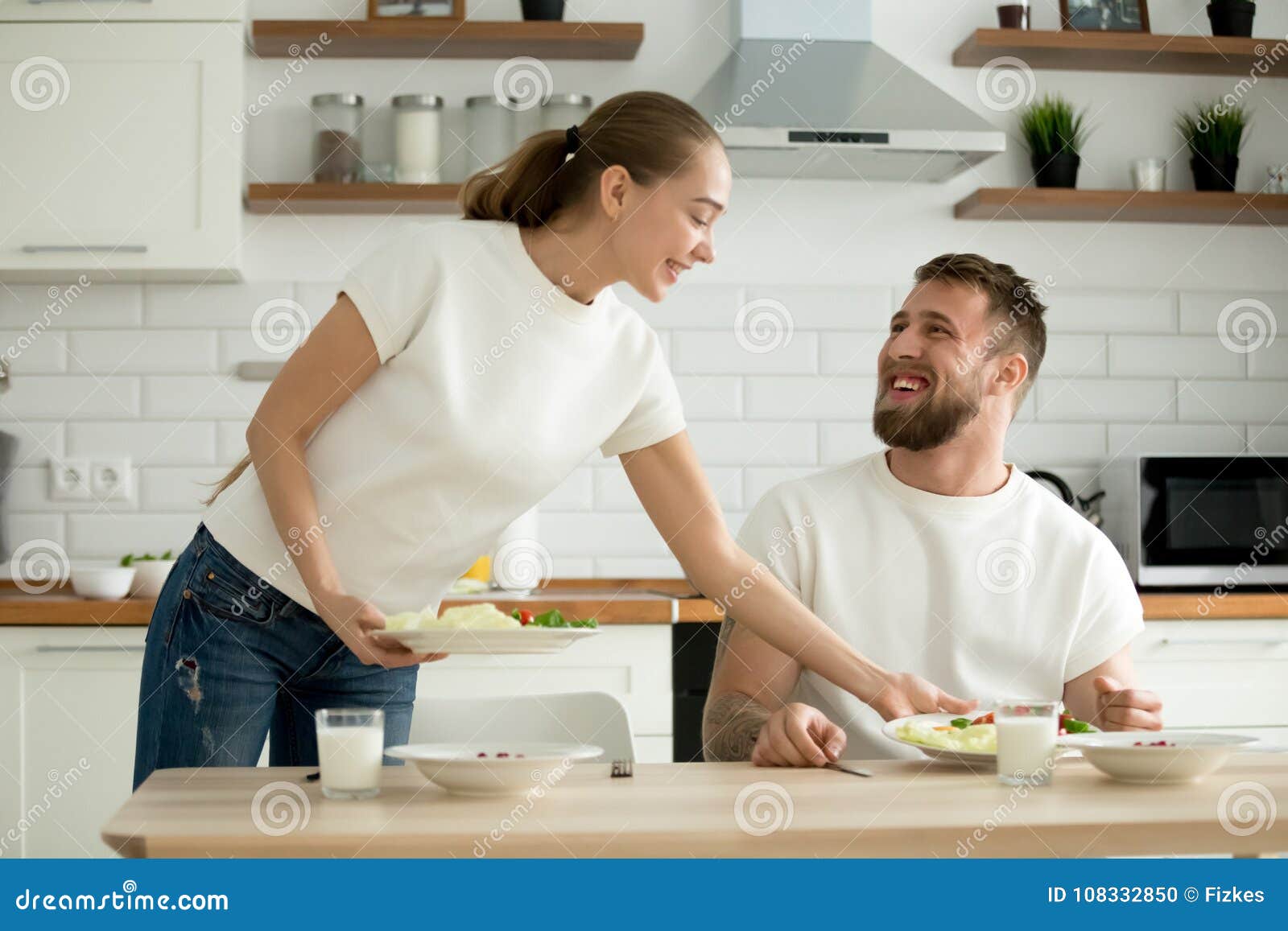 Attractive Wife Serving Food Cooked For Husband In The Kitchen Stock