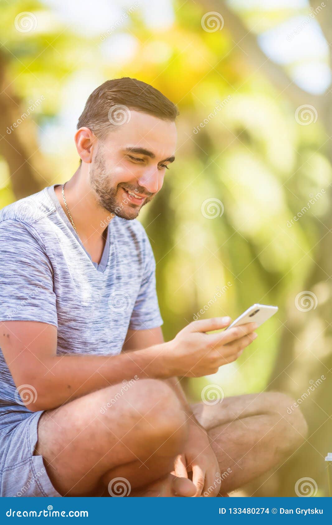 Attractive Young Smiling Man Using Phone in a Public Park Stock Photo ...