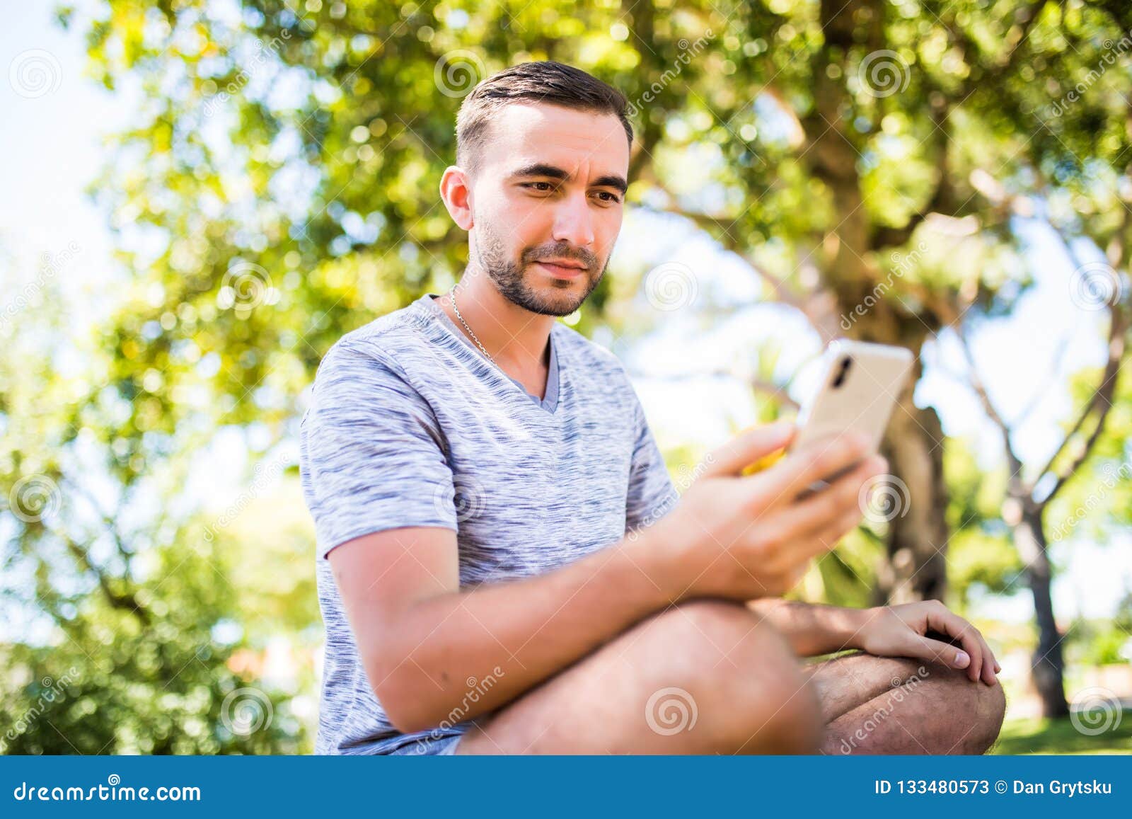 Attractive Young Smiling Man Using Phone in a Public Park Stock Image ...
