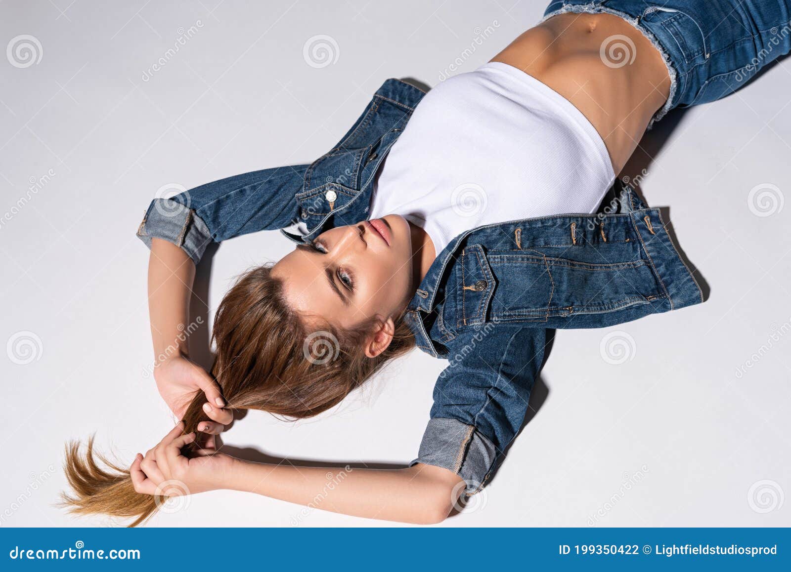 Young Woman in Denim Jacket Lying on White Stock Photo - Image of ...