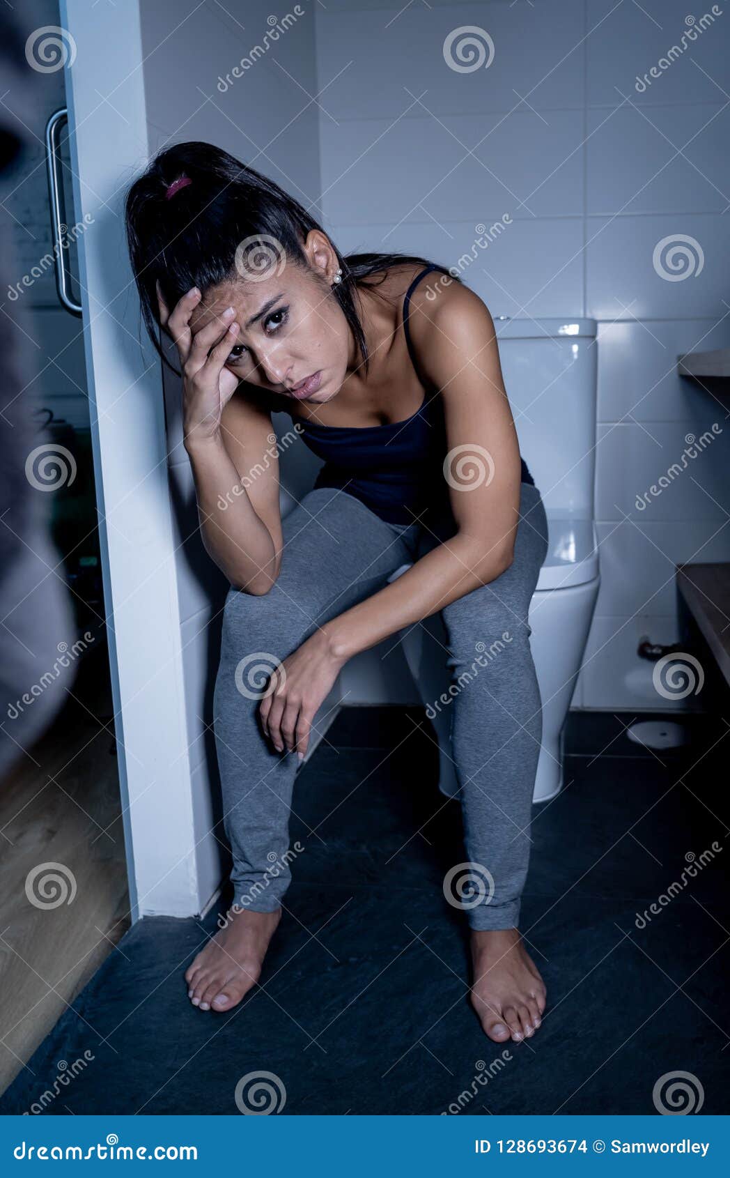 Attractive Young Woman Sitting In The Bathroom Feeling Sick And Looking