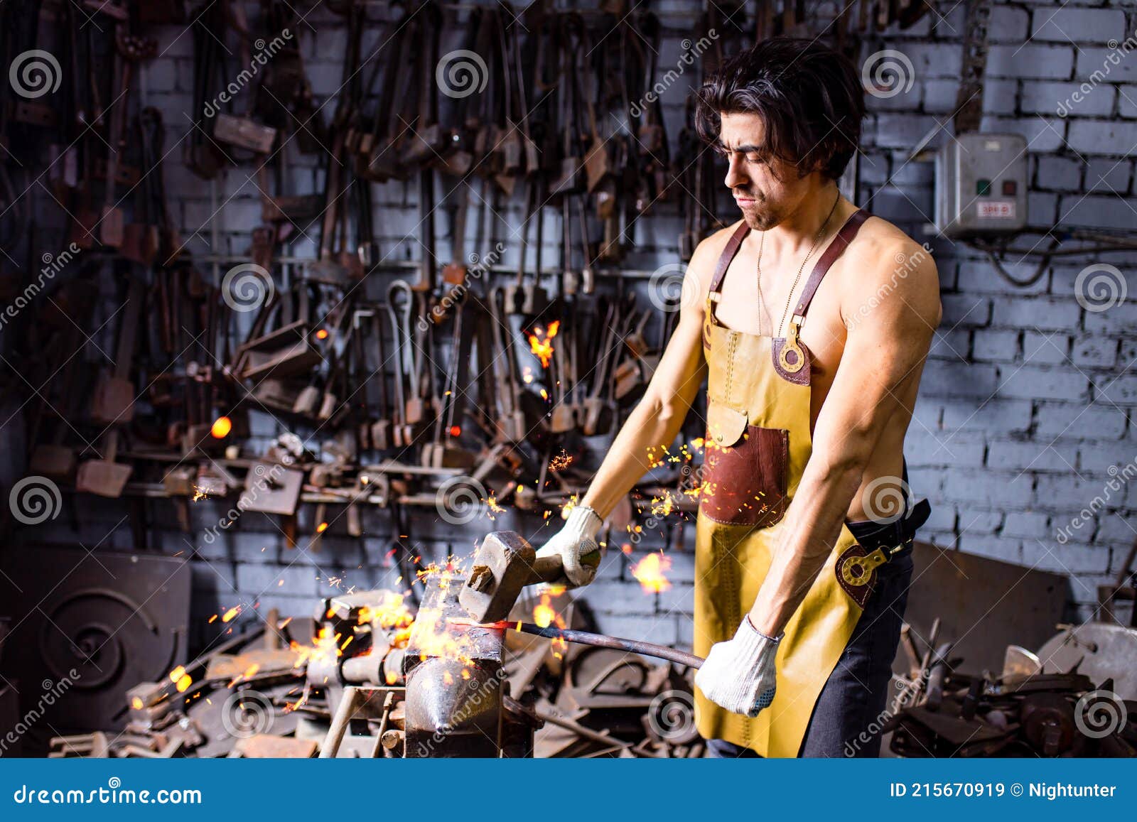 Authentic Blacksmith Man Forges a Metal Product in Dark Indoors Studio ...