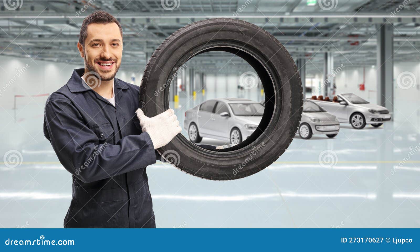 Auto Mechanic Holding a Car Tire and Smiling at Camera in a Garage ...