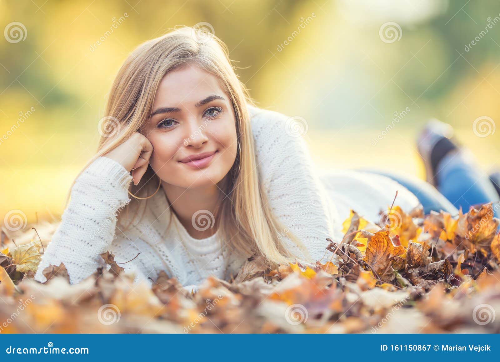 Autumn Portrait Of Young Woman Lying On Maple Leaves In Park Stock
