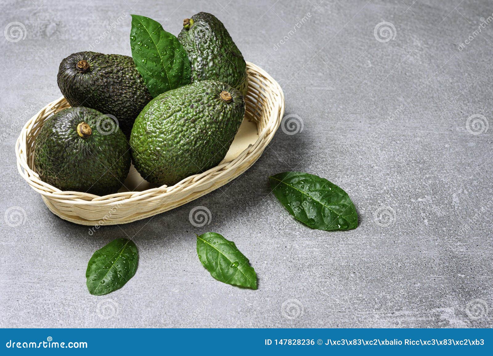 Avocado in Basket of Straw with Leaves on Gray Background Stock Photo ...