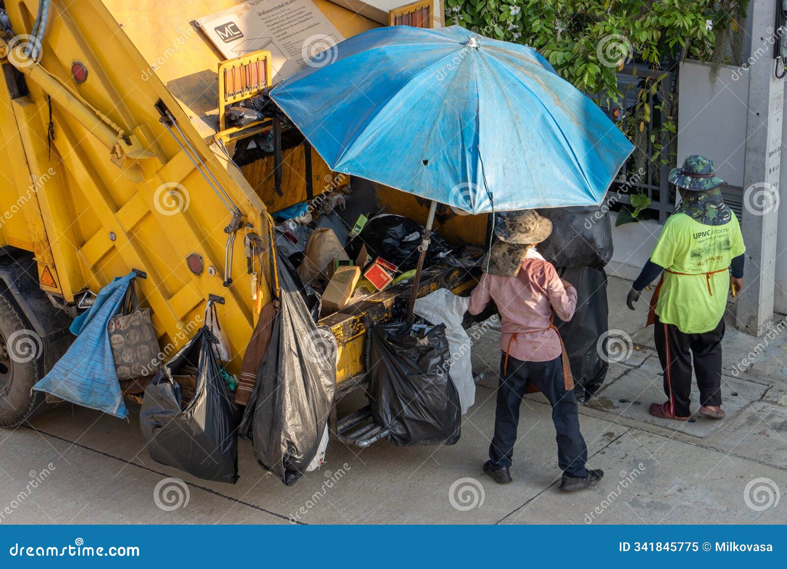 Teamwork of Garbage Men when Loading Waste into the Garbage Truck ...