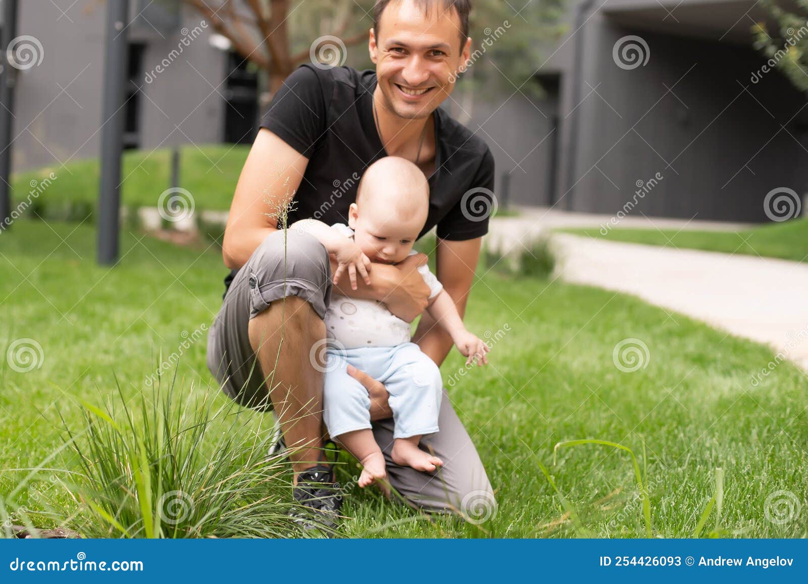Baby Boy Taking First Steps with Father Help in a Park Stock Image ...