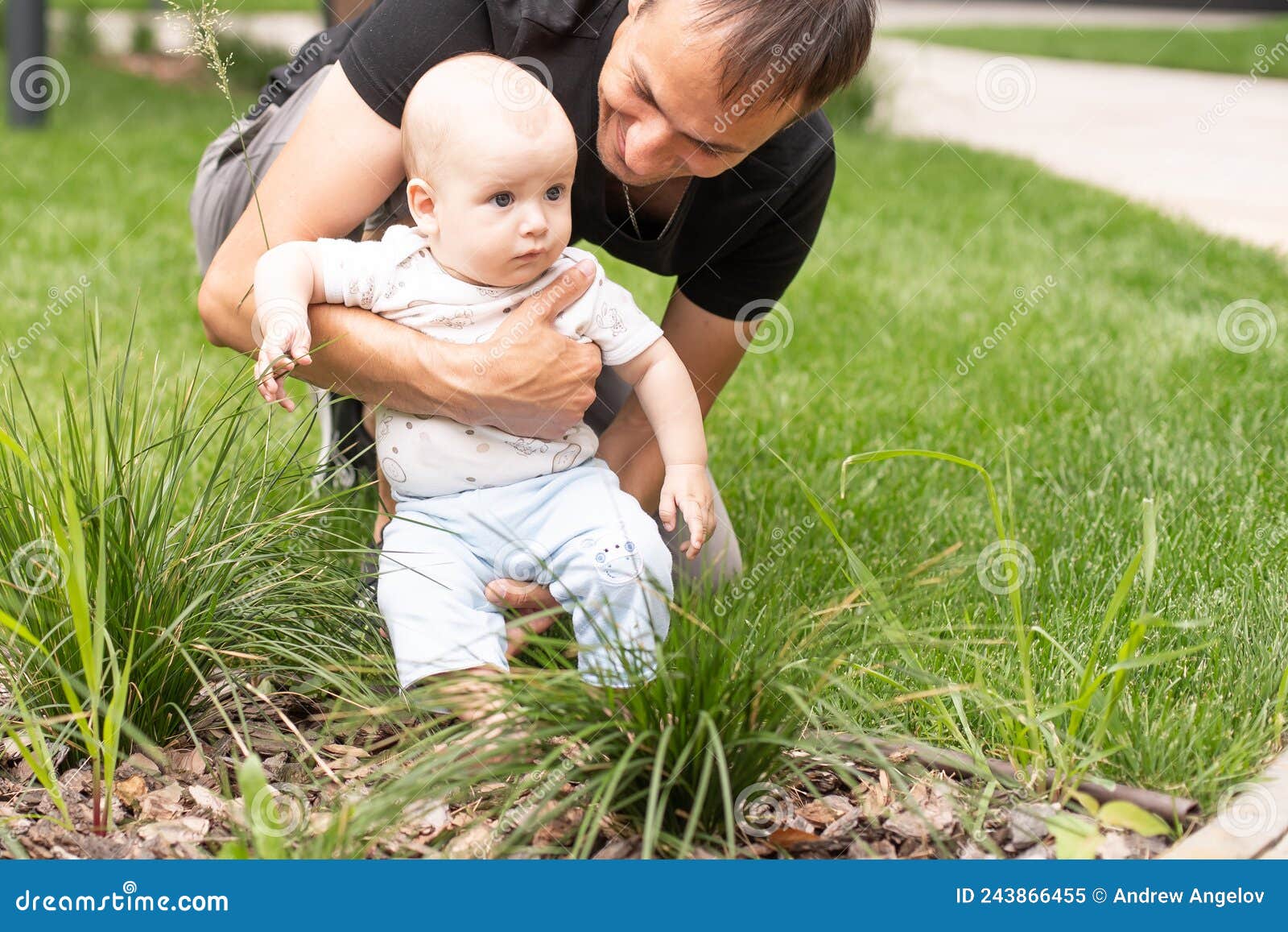 Baby Boy Taking First Steps with Father Help in a Park Stock Image ...