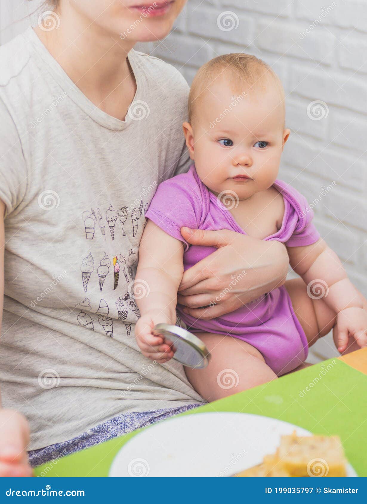 Baby Daughter Sits in Mom`s Arms at the Dining Table in the Kitchen ...