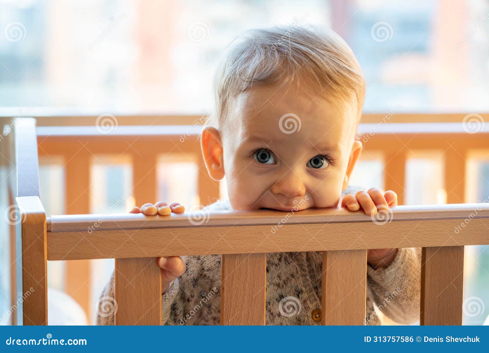The Baby, Embarrassed and Shy, Bites the Side of the Crib Stock Photo ...