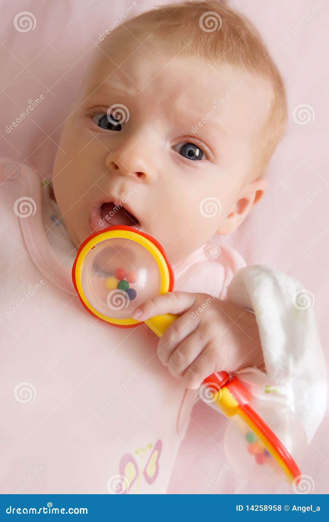 Baby girl holding rattle stock photo. Image of interested - 14258958