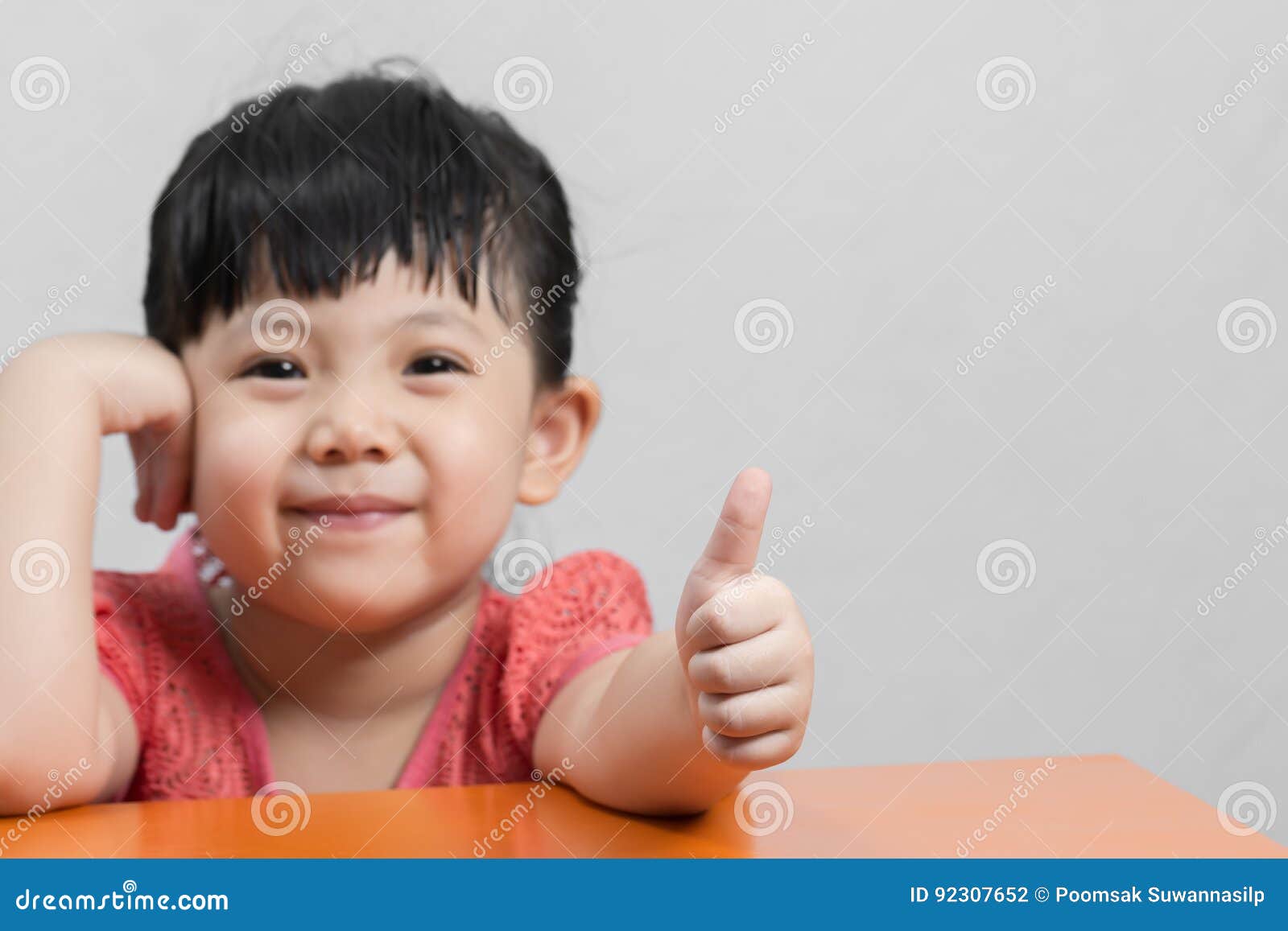 Baby Girl Post Hand with Thumb Up on Orange Table. Stock Photo - Image ...