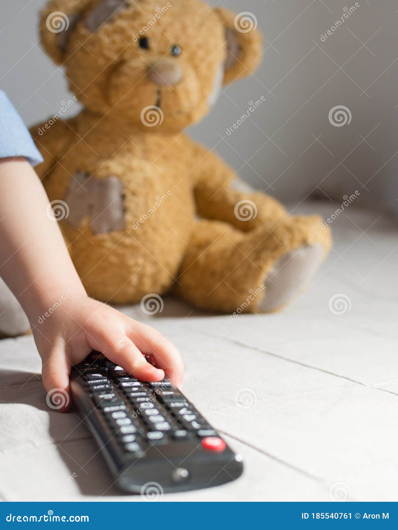 Baby Hand Holding the TV Remote Control, Teddy Bear in the Background ...