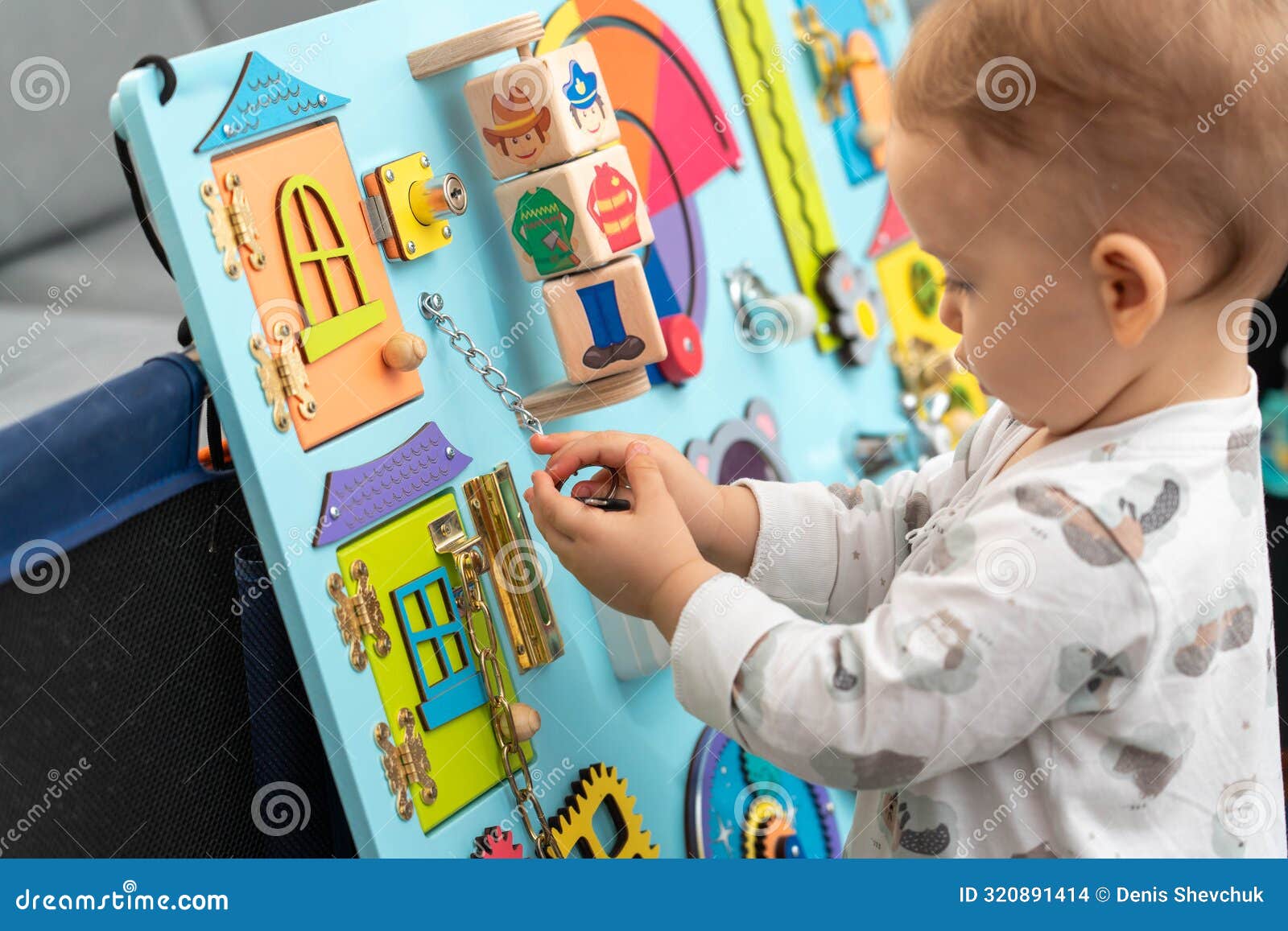 Baby Holding a Key on a Chain while Playing with a Busy Board Stock ...