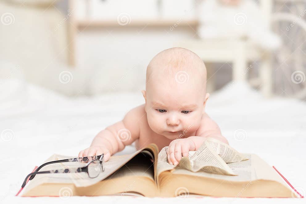 Baby Reading a Book or Looking at it in the Nursery, Learning and ...