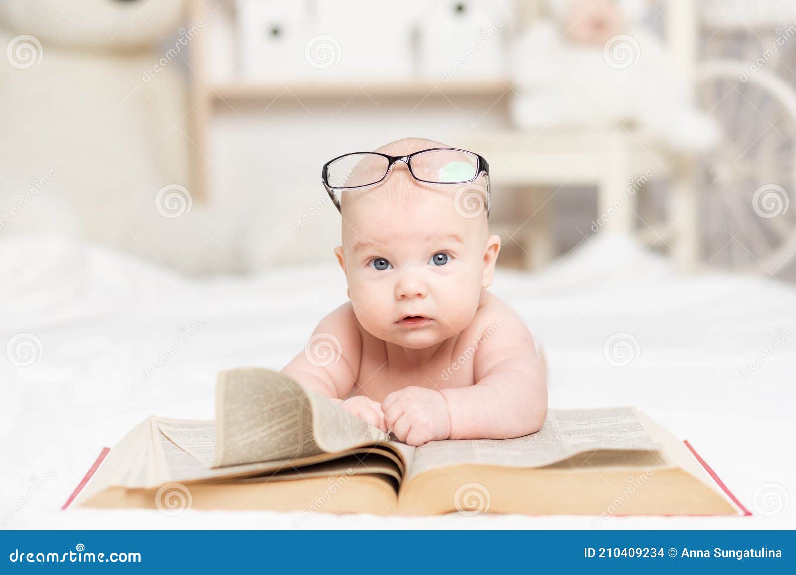 Baby Reading a Book or Looking at it in the Nursery, Learning and ...