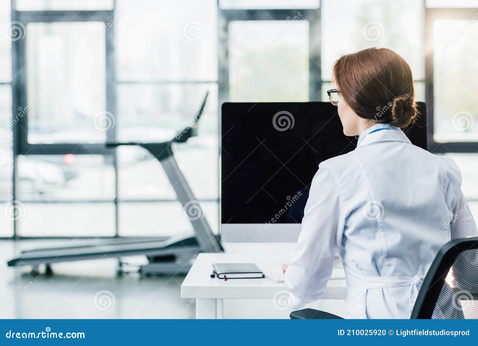 Back View of Doctor in White Coat Sitting at Computer Desk at Gym ...