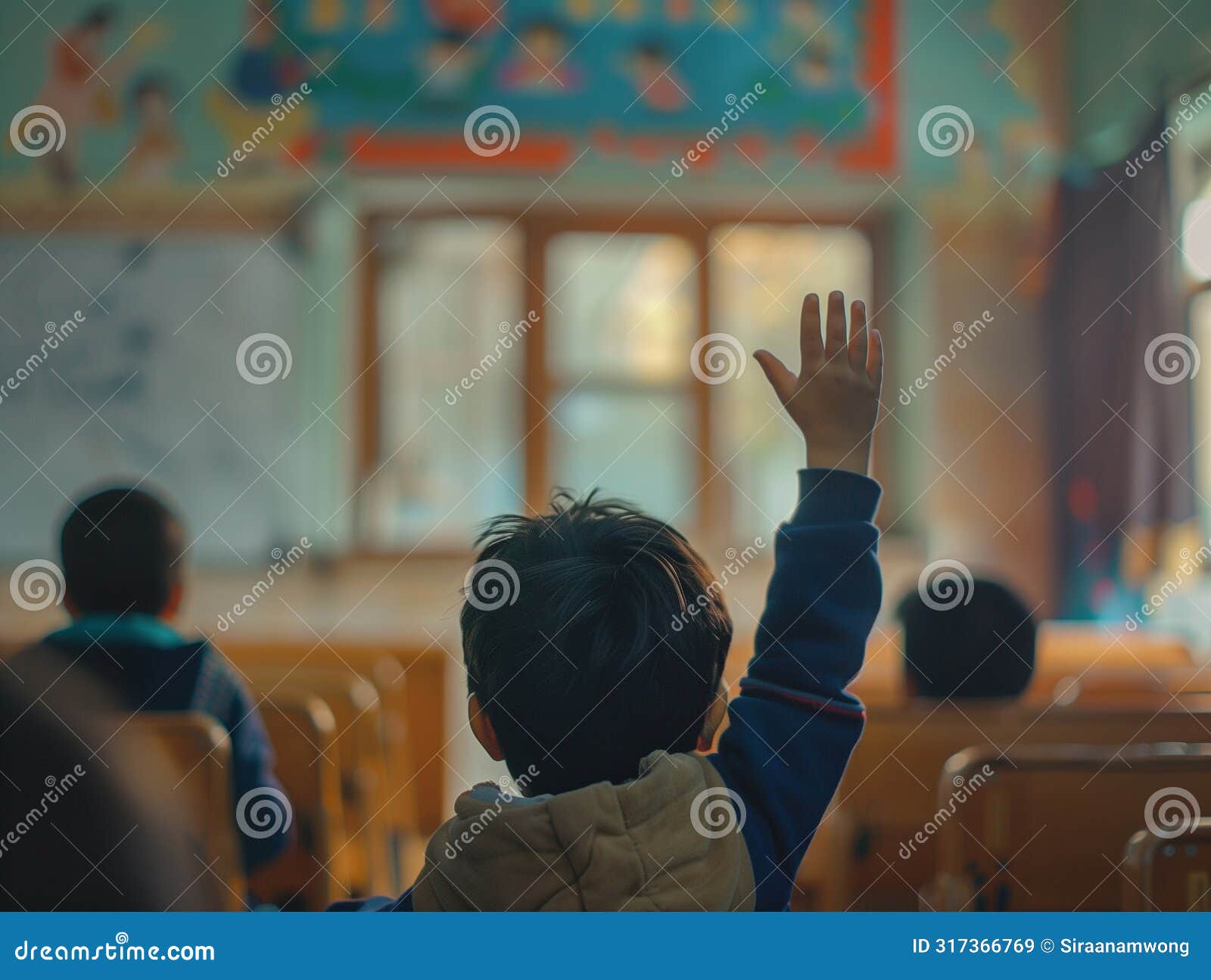 Back View of Elementary Student Raising His Hand To Answer a Question ...