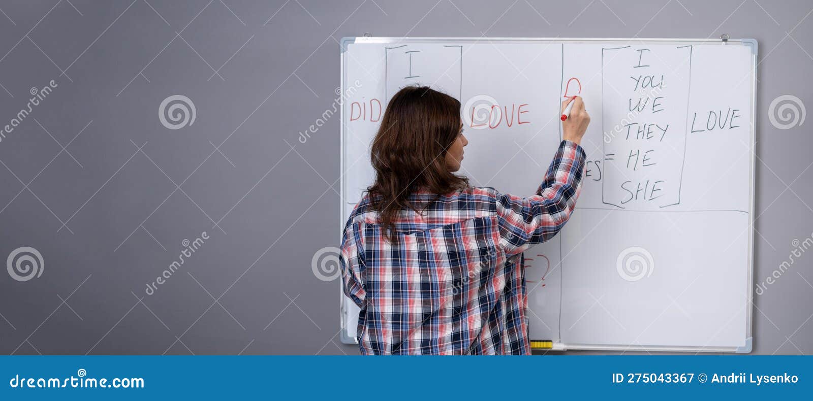 Back View of Female Teacher Standing at a Whiteboard, Writing on the ...