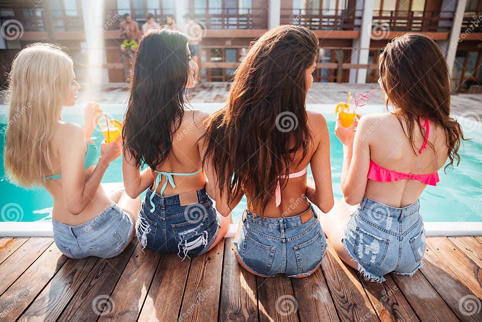 Back View Of Happy Women Drinking Cocktails Near Swimming Pool Stock