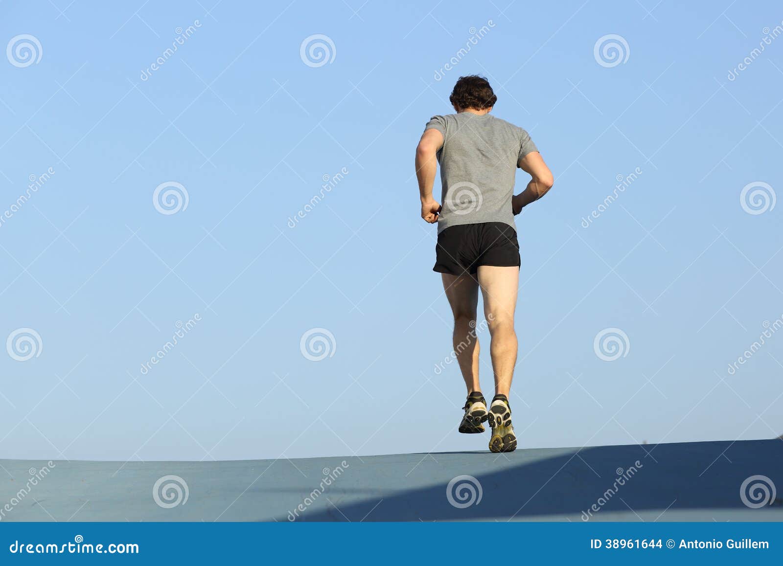 Back View of a Jogger Man Running Against Blue Sky Stock Photo - Image ...