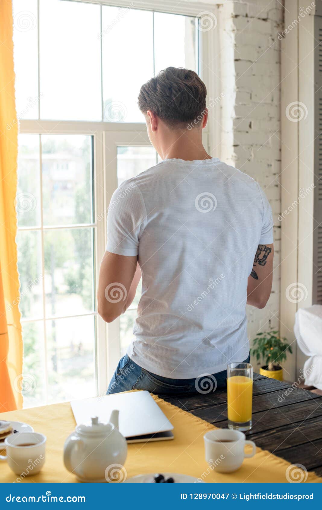 Back View of Man Standing at Window with Breakfast on Table Stock Image ...