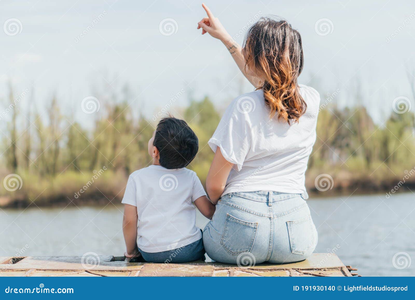 View of Mother Pointing with Finger and Sitting Near Son Stock Photo ...