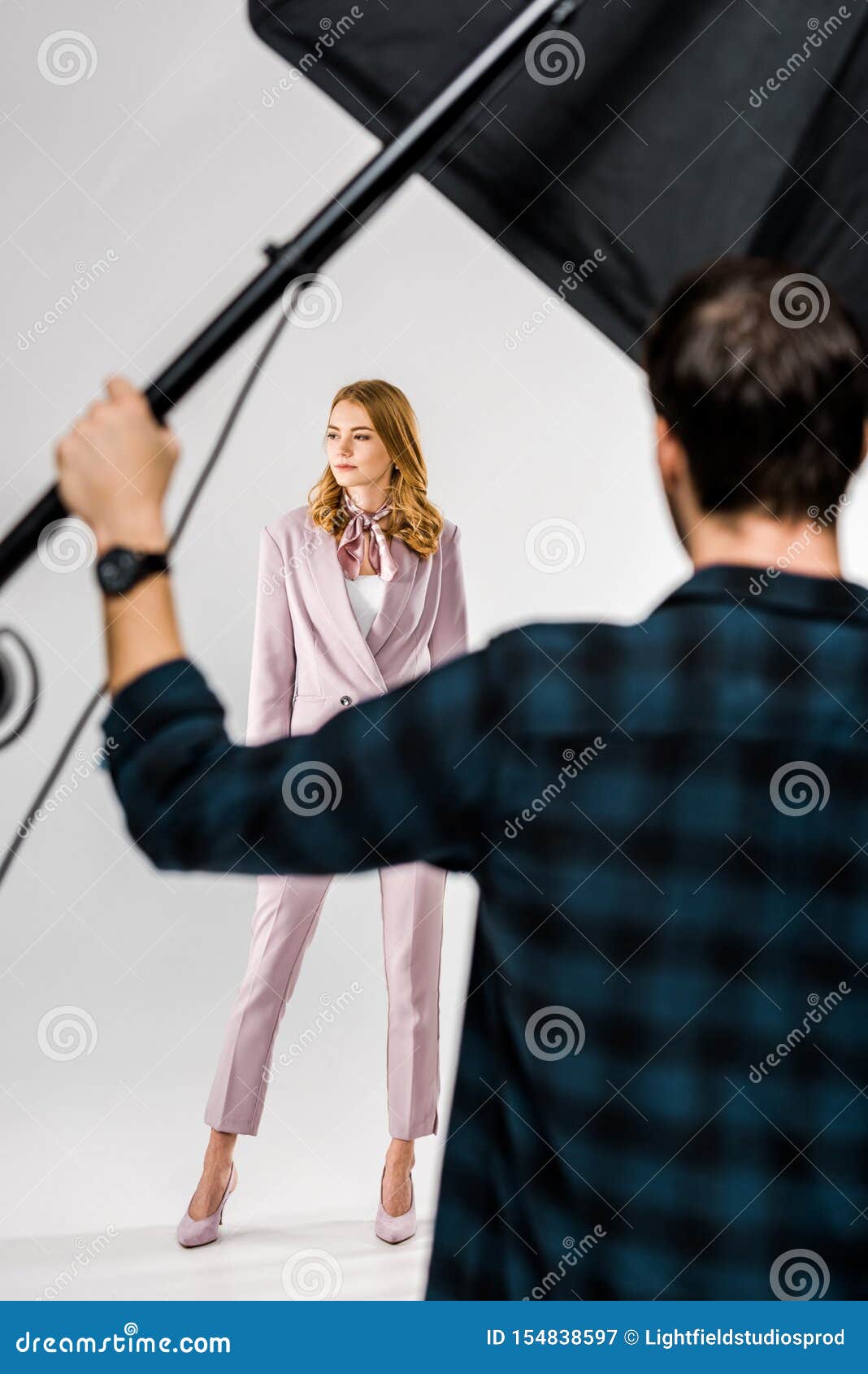 Back View of Photographer Working with Lighting Equipment while Female ...