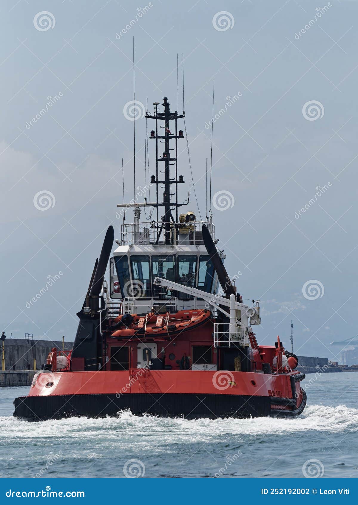 Back View of a Powerful Tugboat Moving Fast Next To Breakwater To the ...
