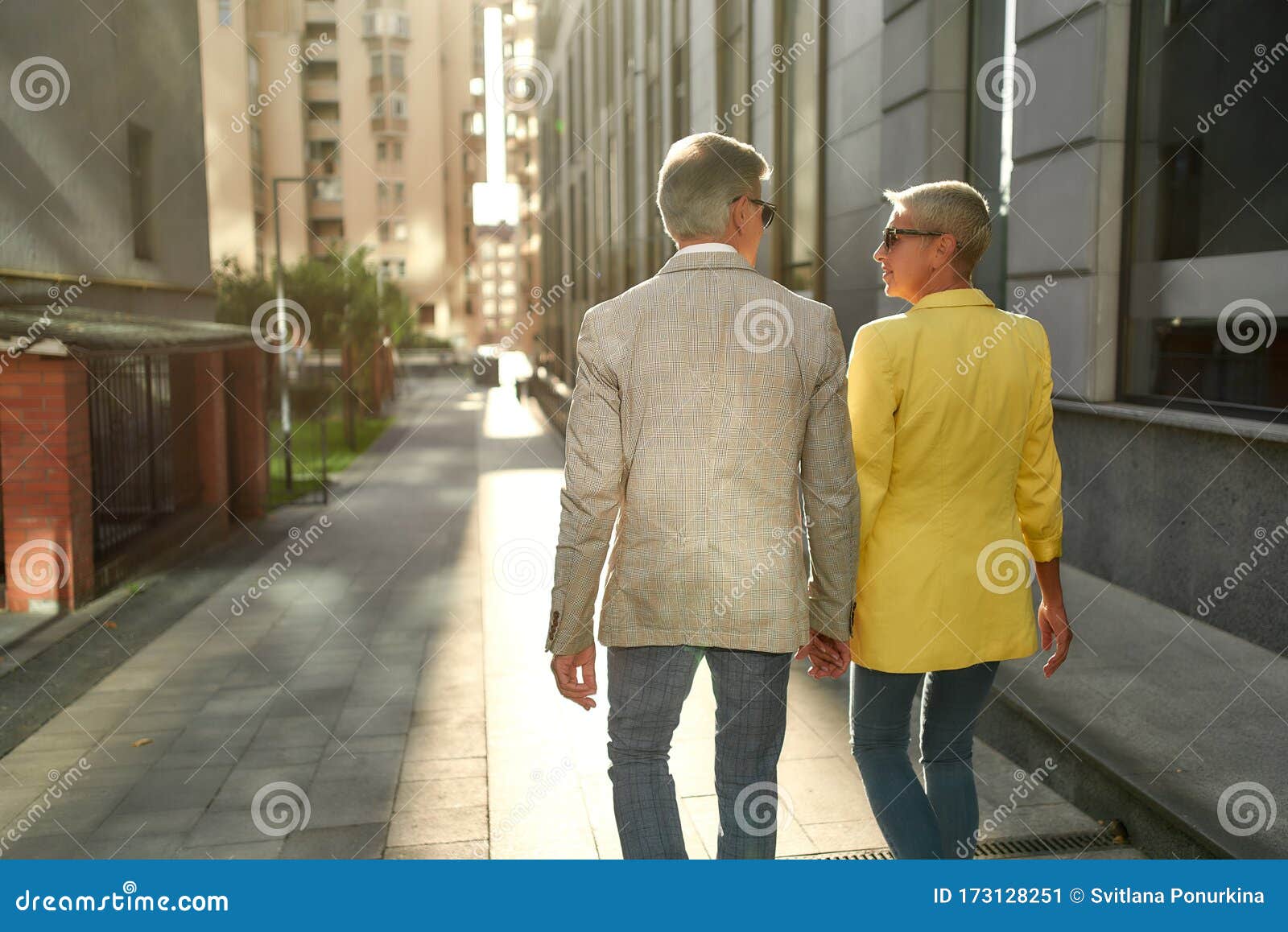 Back View Of Stylish Middle Aged Couple Holding Hands And Looking At