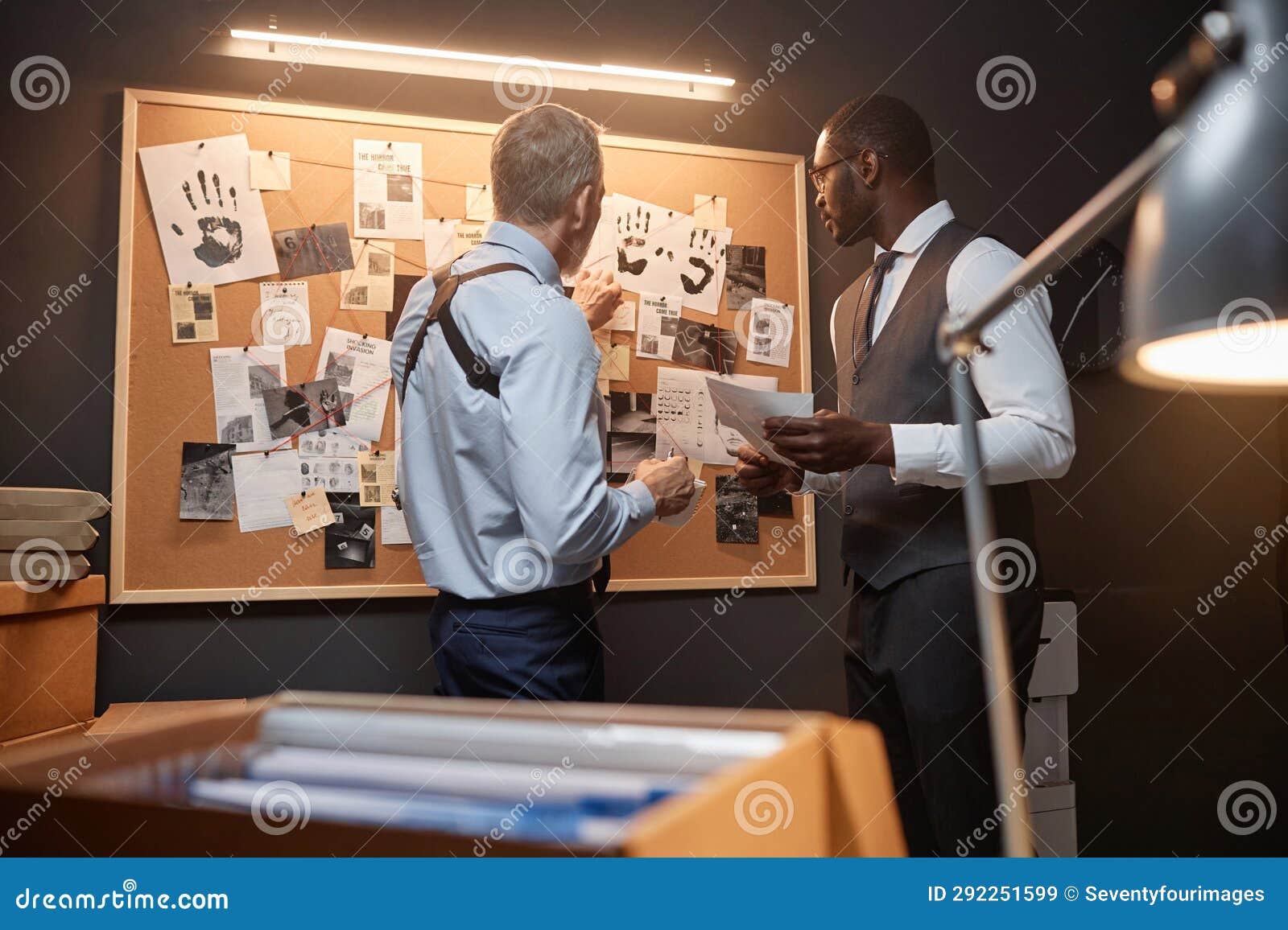 Back View of Two Detectives Discussing Case Standing by Evidence Board ...