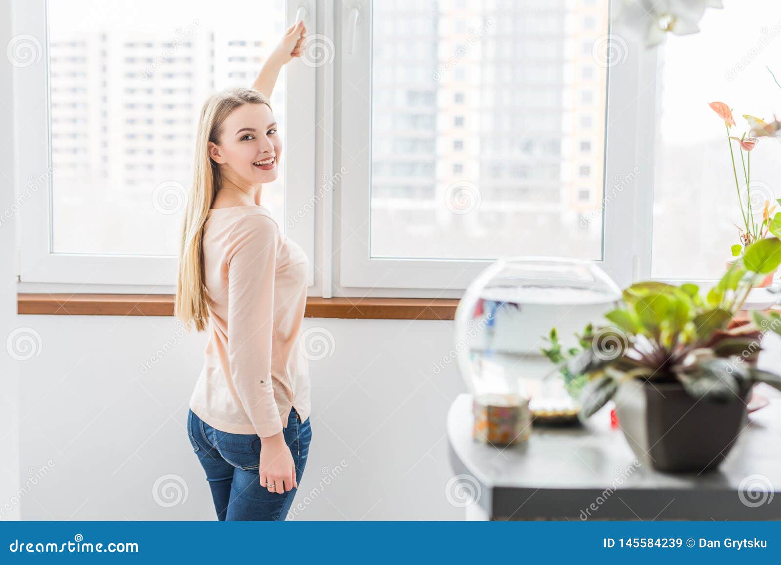 Back View of a Woman Looking Outdoors through a Window and Opening ...