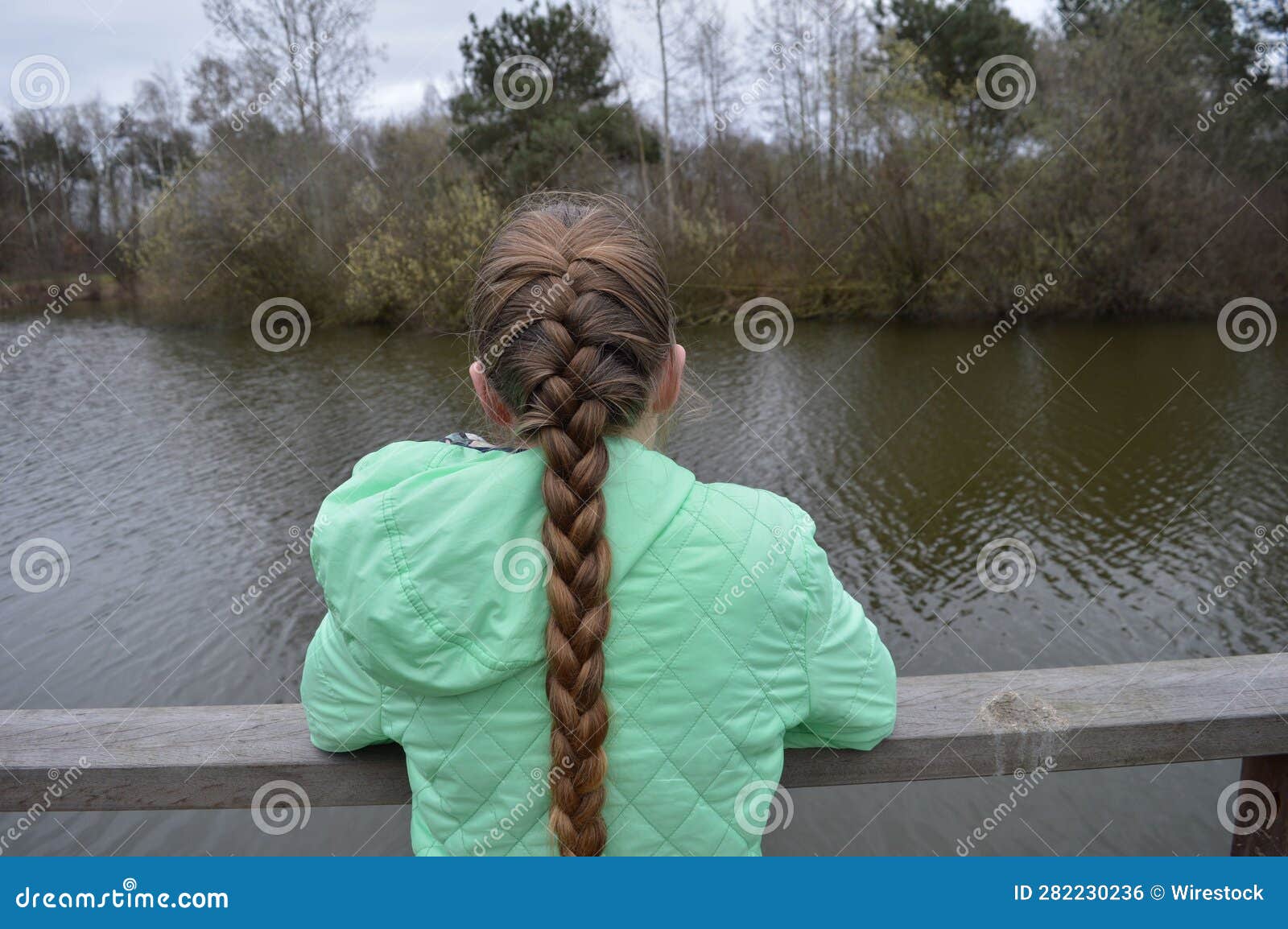 Back View of a Young Female with Long Hair in a Braid and a Green ...