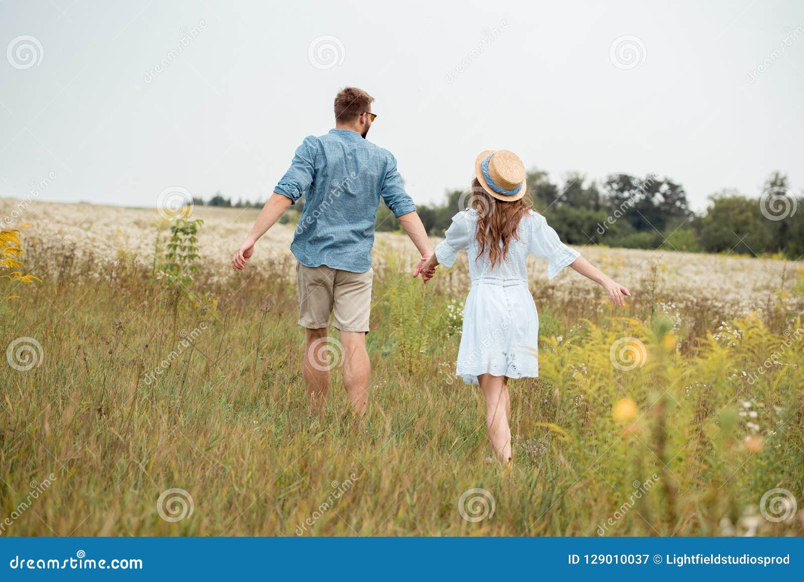 Back View of Young Lovers Holding Hands while Running in Field Stock ...