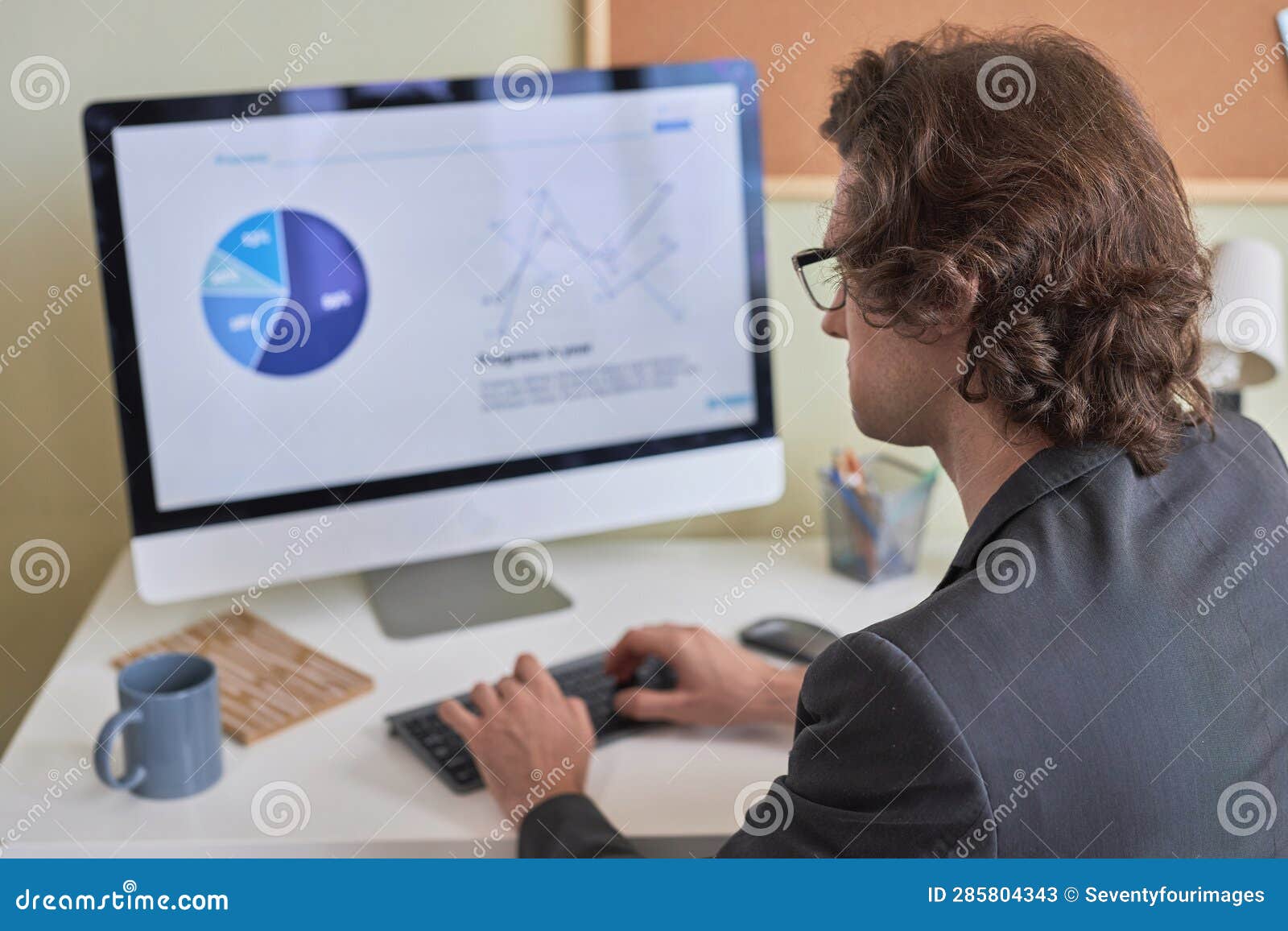 Back View of Young Man Using Computer at Desk in Office and Analyzing ...