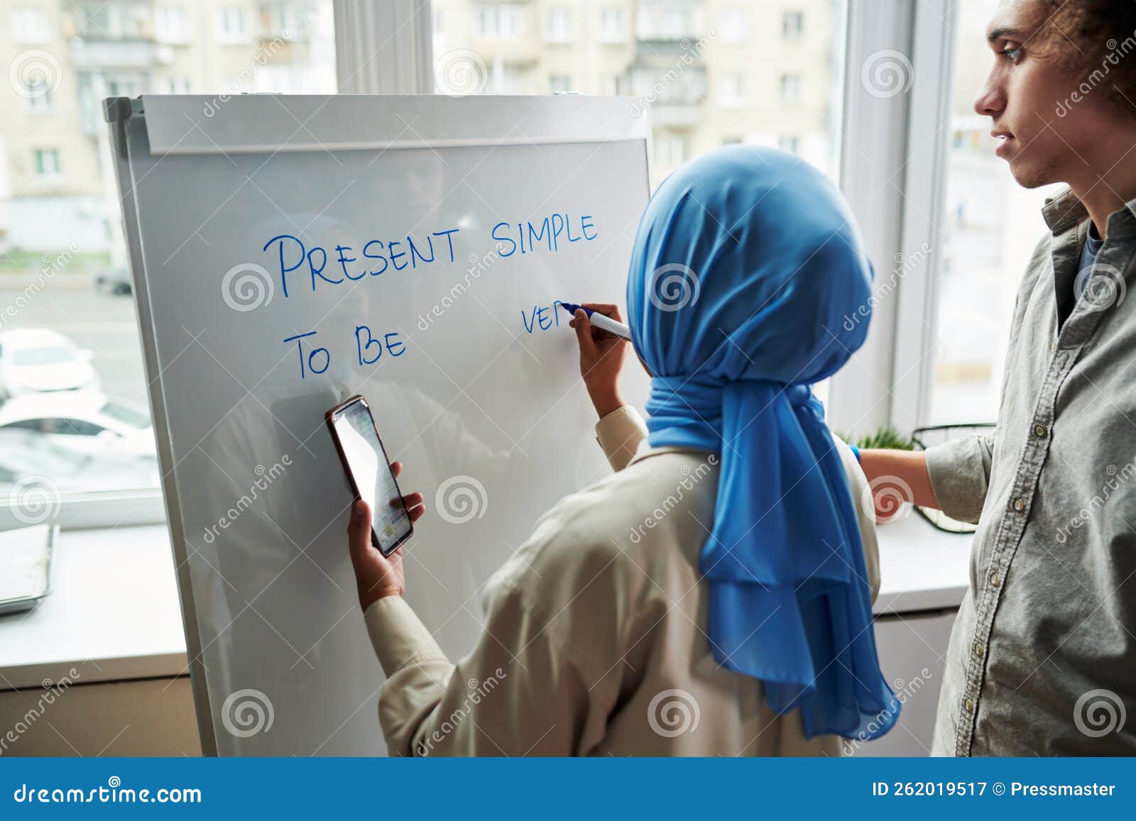 Back View of Young Muslim Female Teacher Explaining Guy Present Simple ...
